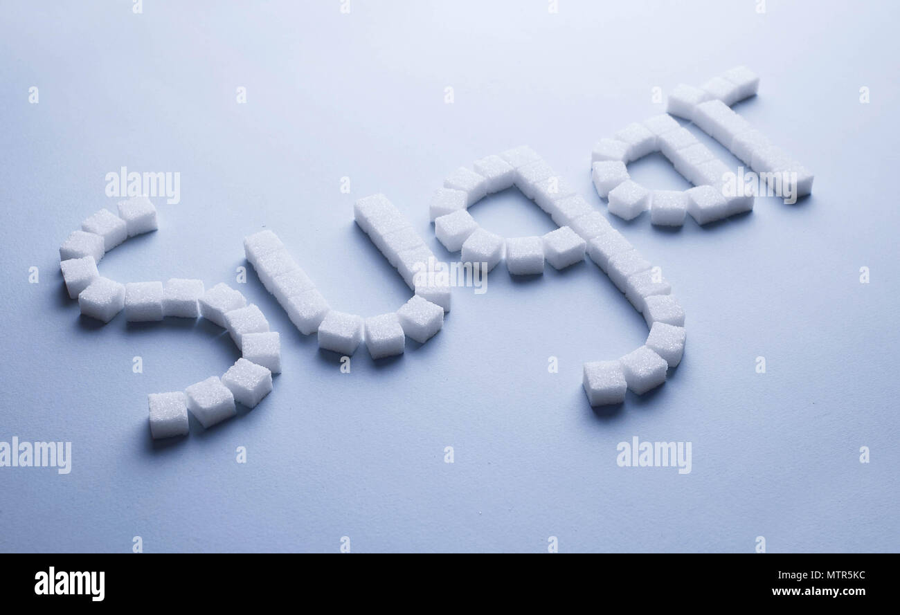 Concept: Sugar text made of white sugar cubes over blue background ...