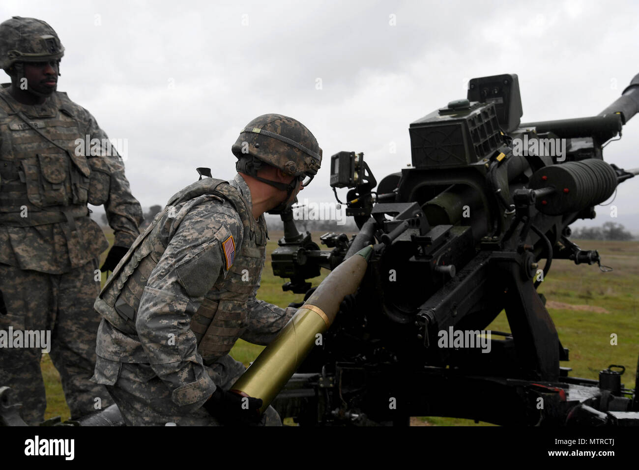 An Army Soldier assigned to Bravo Battery, 1-143rd Field Artillery, loads an M119A3 105mm ...