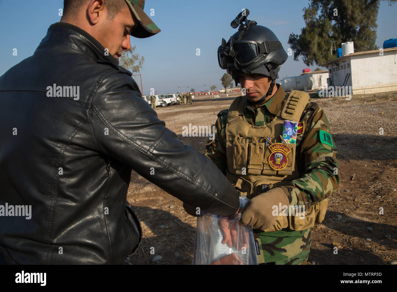 An Iraqi security forces soldier searches a fellow ISF soldier during ...