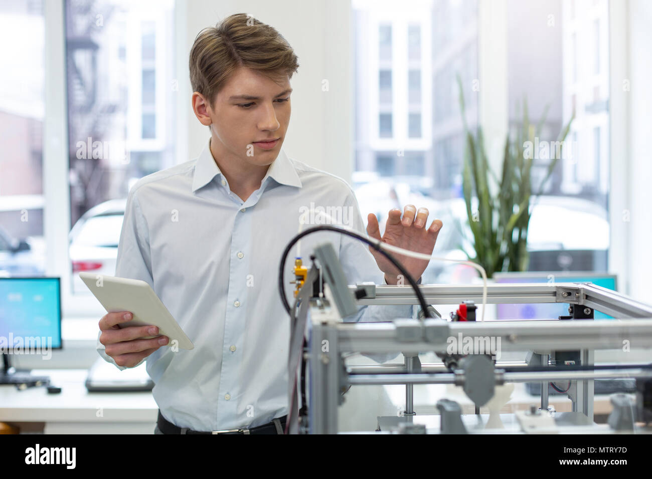 Pleasant young trainee learning 3D printer mechanism Stock Photo - Alamy