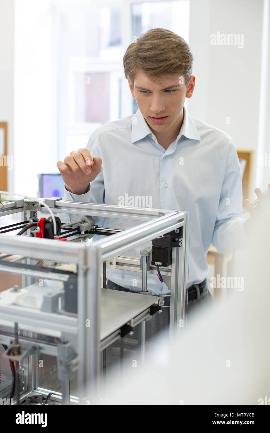 Pleasant young man looking for error in 3D printer mechanism Stock ...