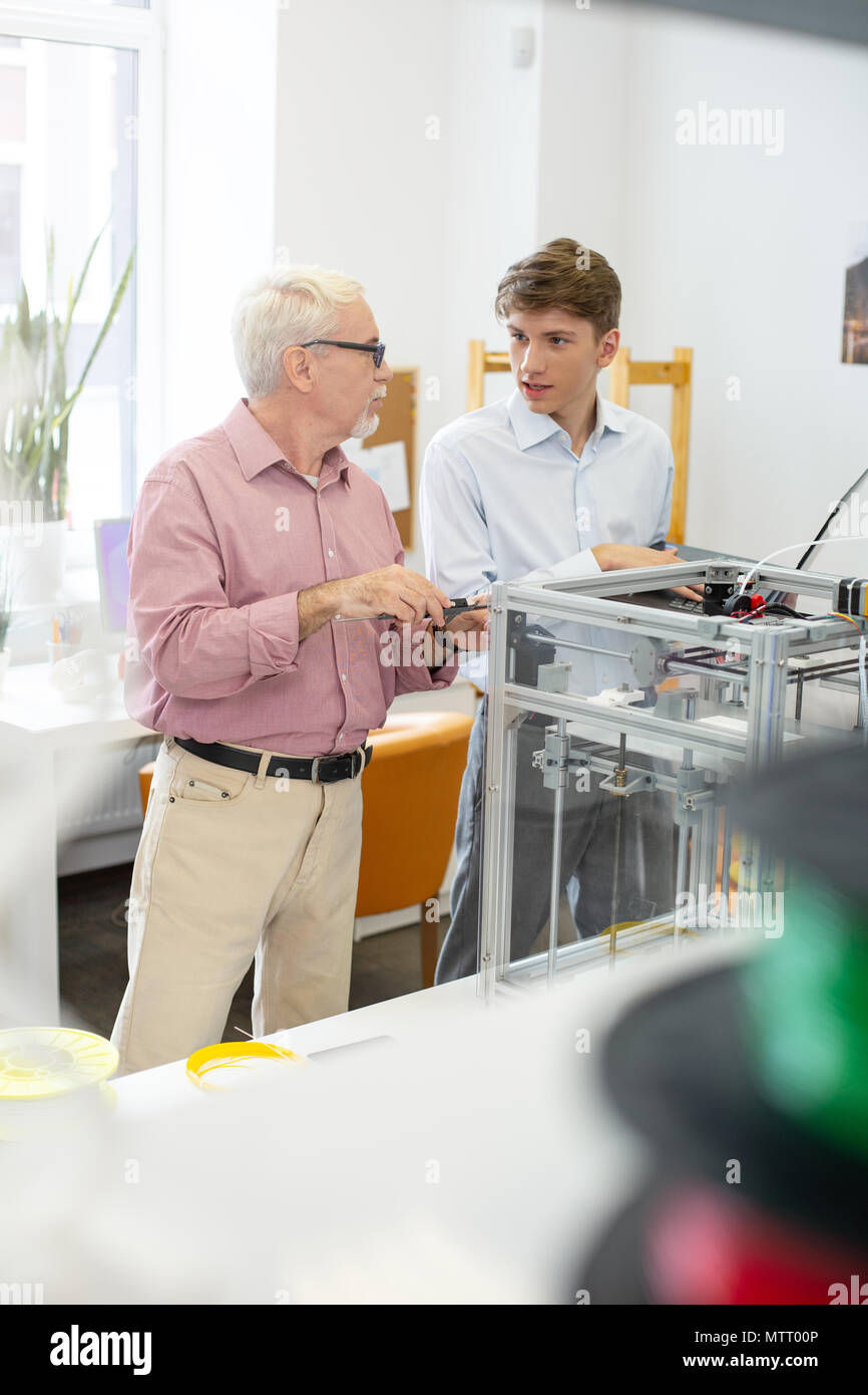 Young man asking supervisor questions about 3D printing Stock Photo - Alamy