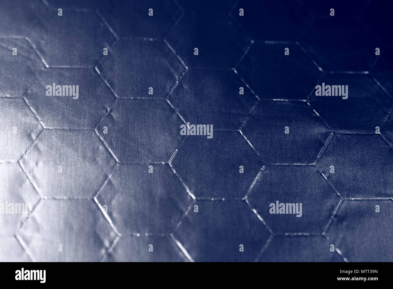 Macro view of aluminium foil with an hexagonal pattern and a blue ...