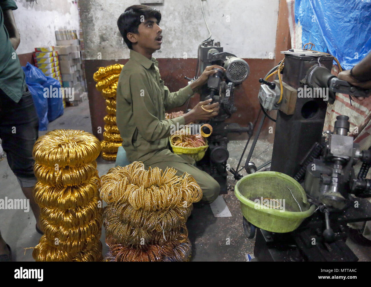 Pakistani workers are busy preparing glass bangles in a local factory ...