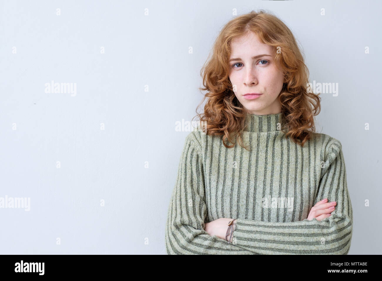 Portrait of aggravated sad woman with long red hair with crossed hands ...