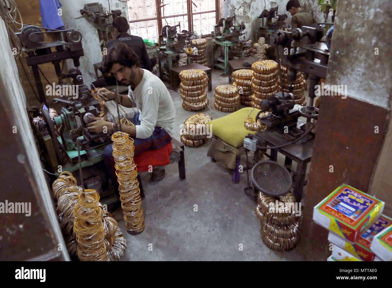 Pakistani workers are busy preparing glass bangles in a local factory ...