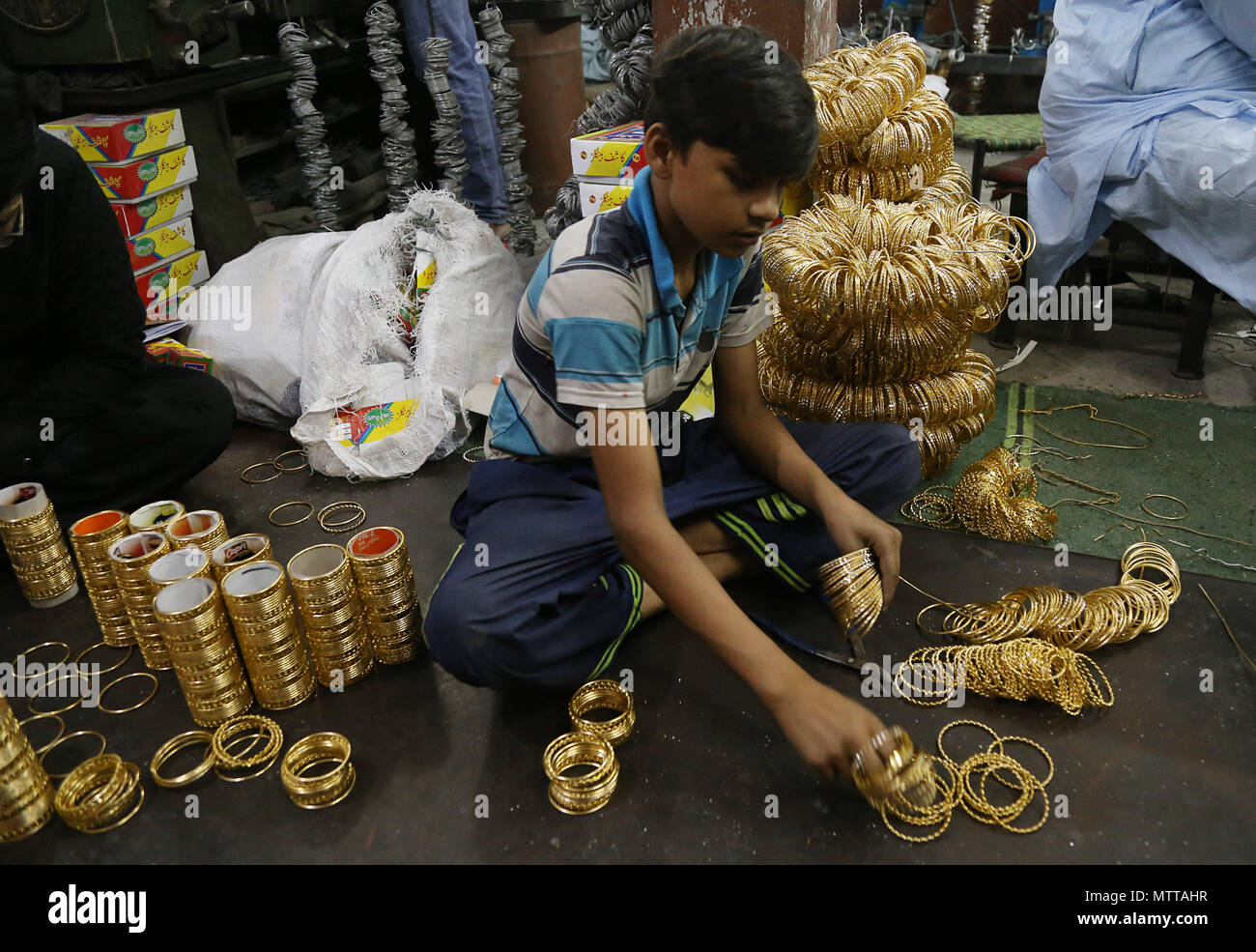 Pakistani workers are busy preparing glass bangles in a local factory ...