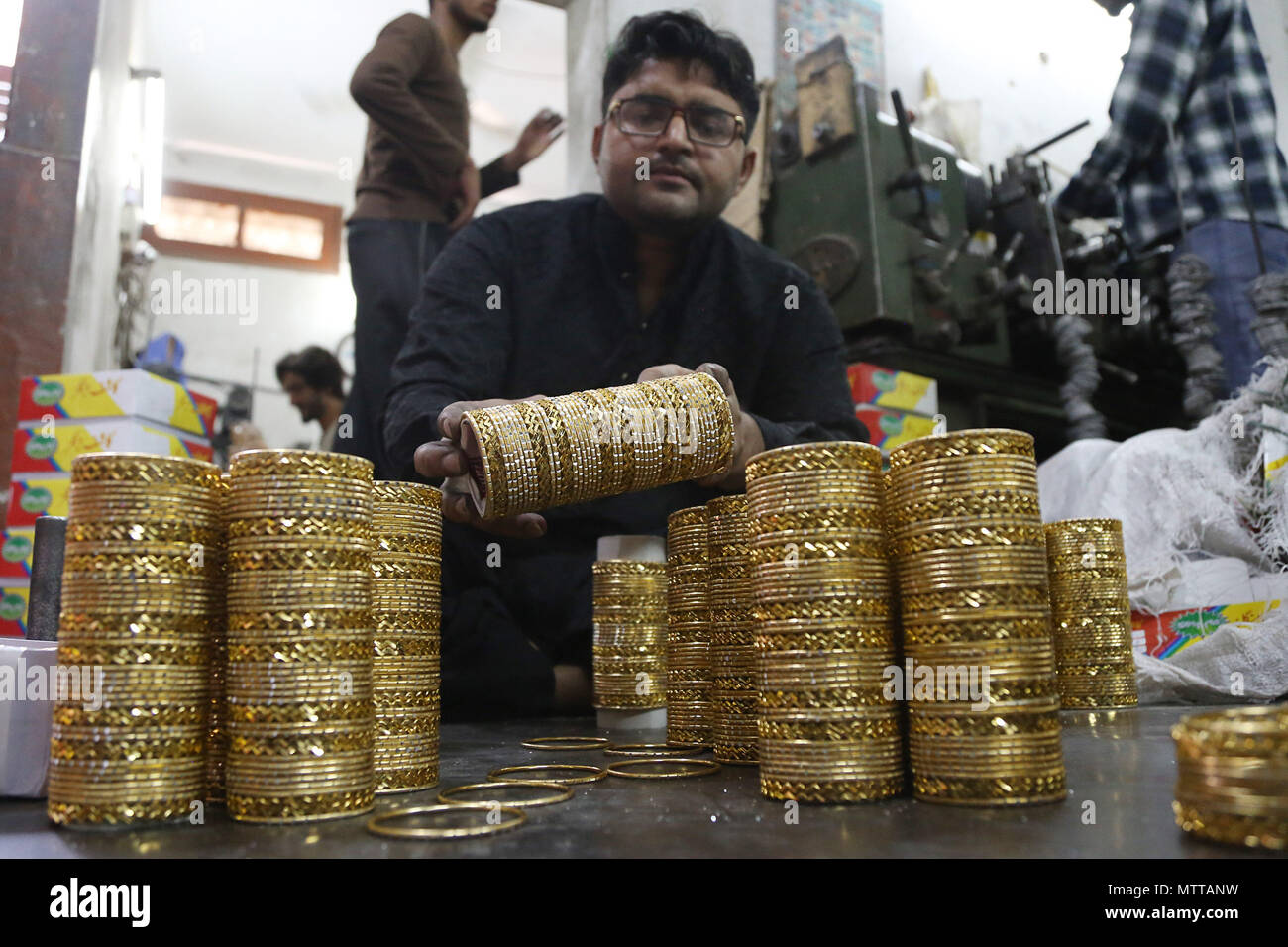 Pakistani workers are busy preparing glass bangles in a local factory ...