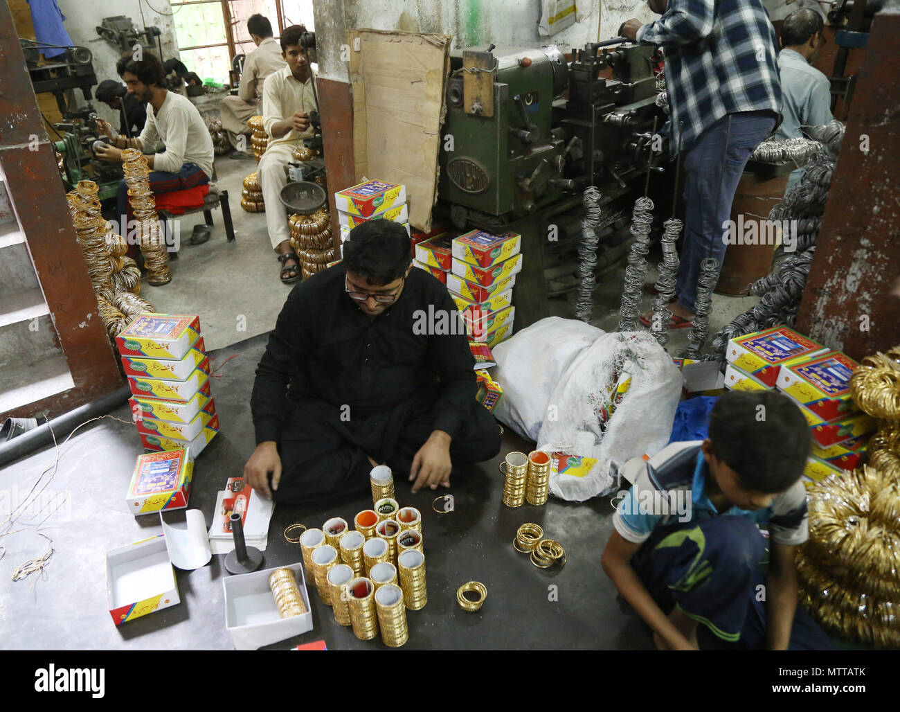 Pakistani workers are busy preparing glass bangles in a local factory ...