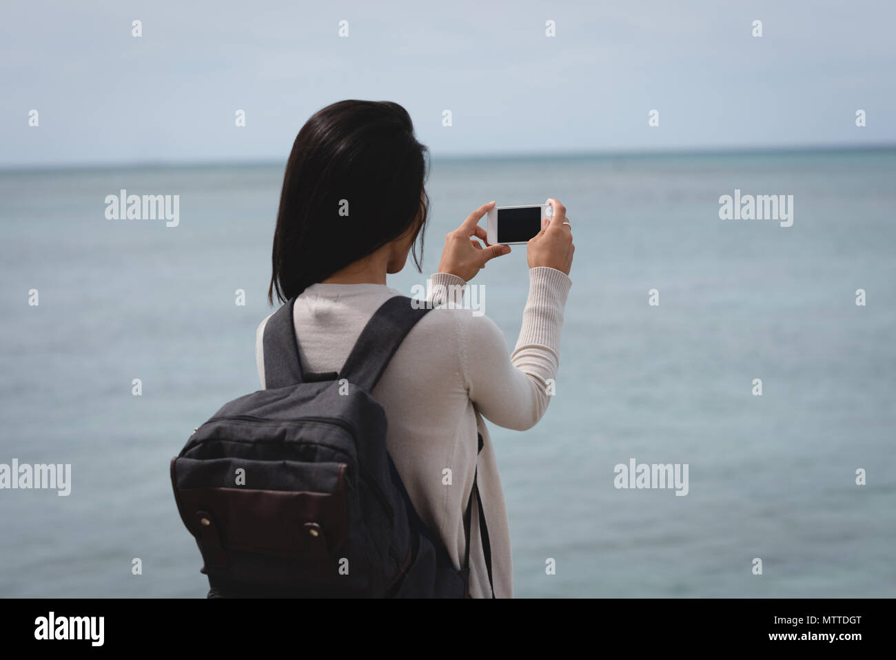 Woman clicking photo of sea with mobile phone Stock Photo - Alamy
