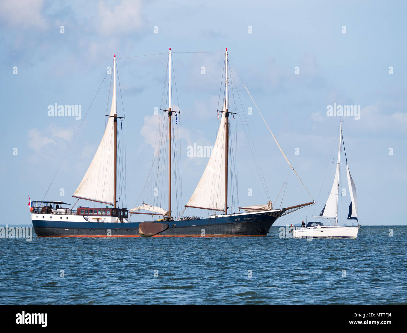 Authentic sailing ship, schooner, sailing very close to small sailboat ...