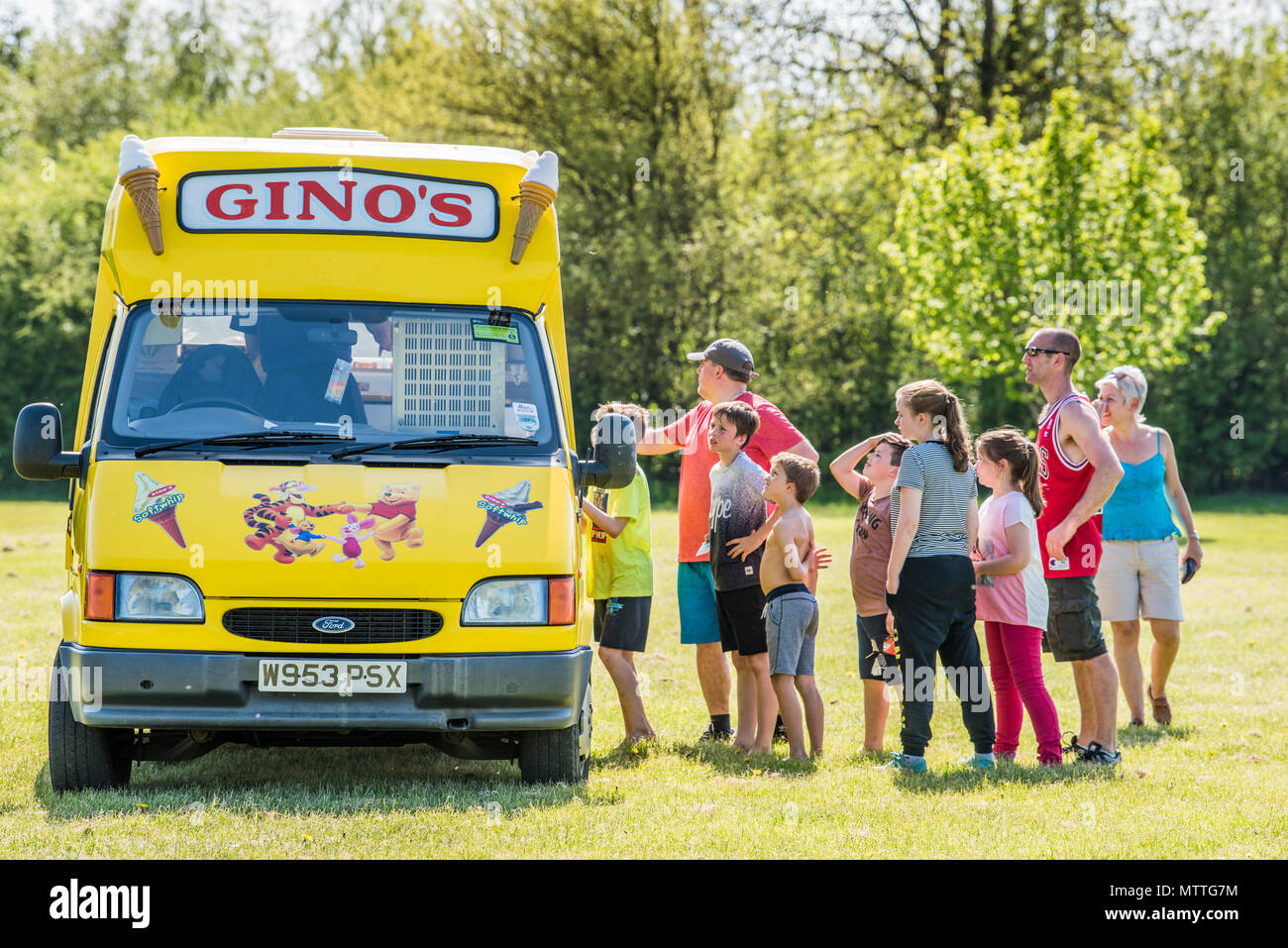 Queue for an ice-cream from Gino's van in a field on a hot day at ...