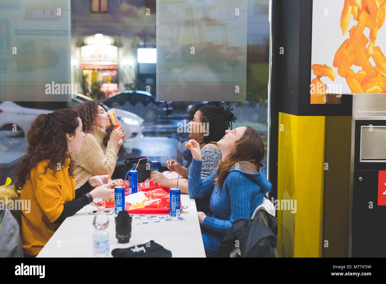 four young women multiethnic indoor eating at fast food - food and ...