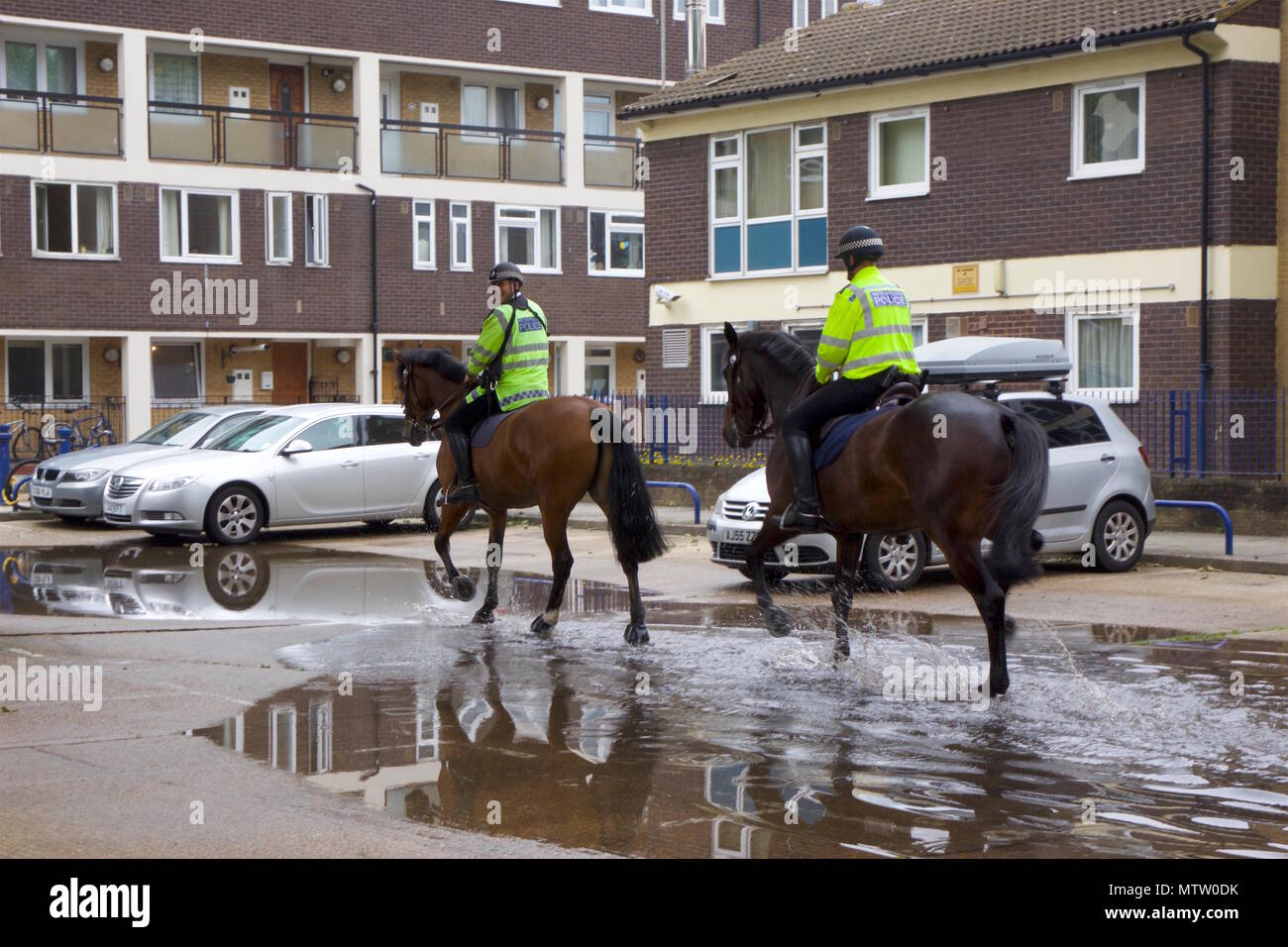 Two Metropolitan Policemen riding horses that are trotting through a ...