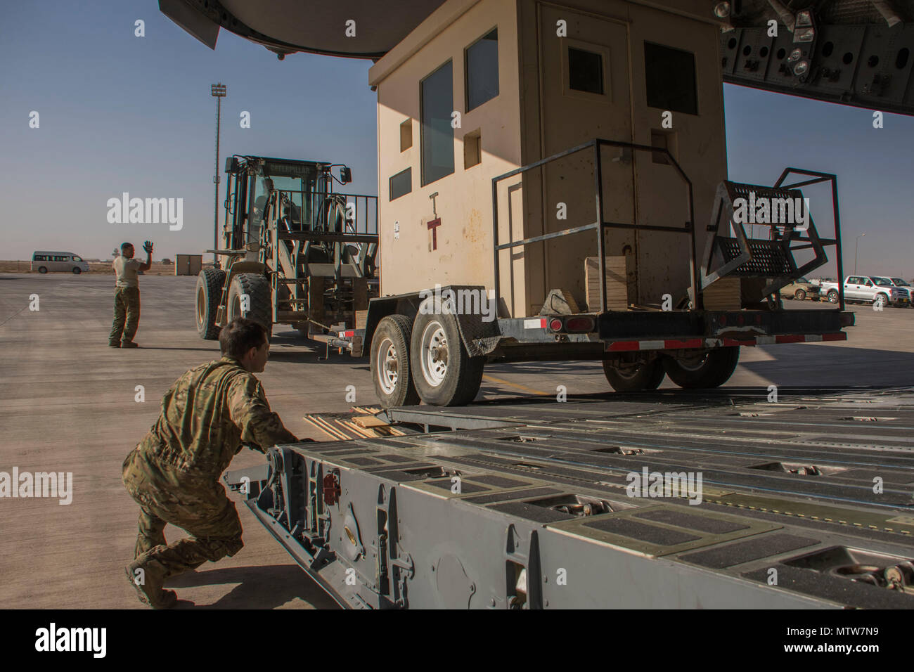 An aerial porter, left, and a loadmaster, right, work together to guide ...