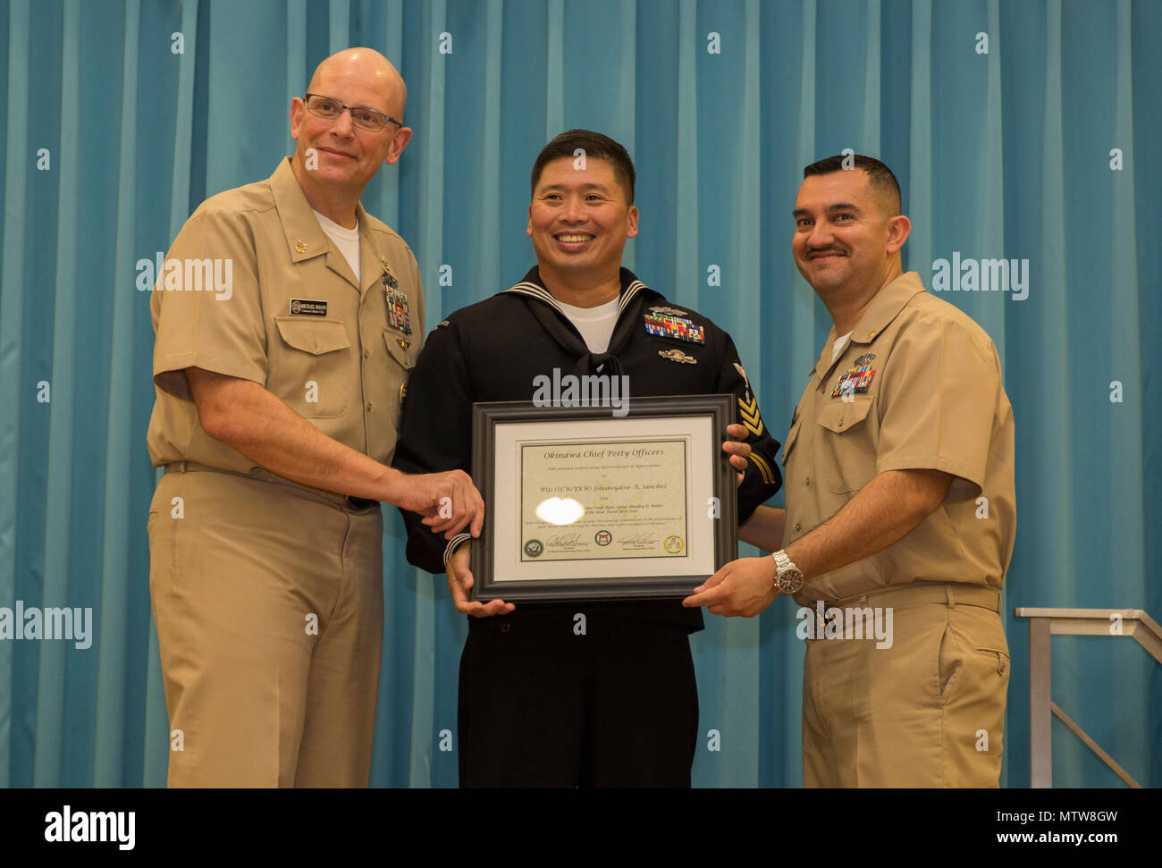 Navy Petty Officer 1st Class Johan Sanchez (center) presents his award ...