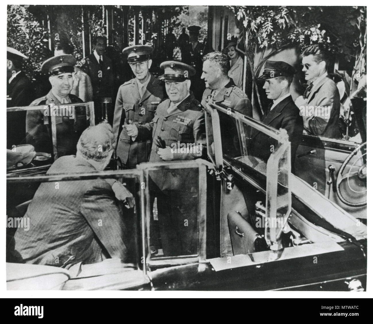 Pres Roosevelt (in veh) is greeted by LtoR Col Knighton, Brig. Gen ...
