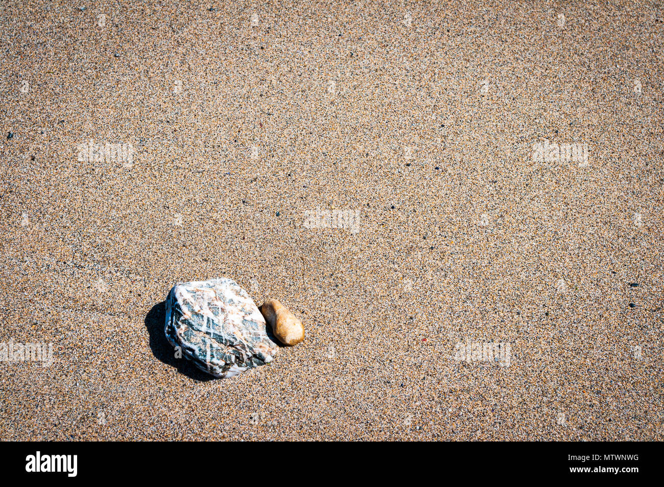 Two pebbles on a sandy beach background Stock Photo - Alamy