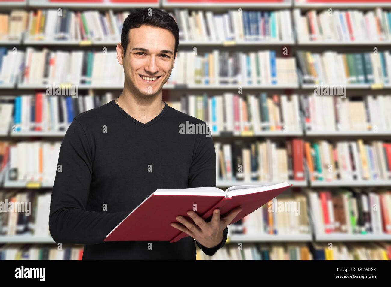 Guy reading a book in a library Stock Photo - Alamy