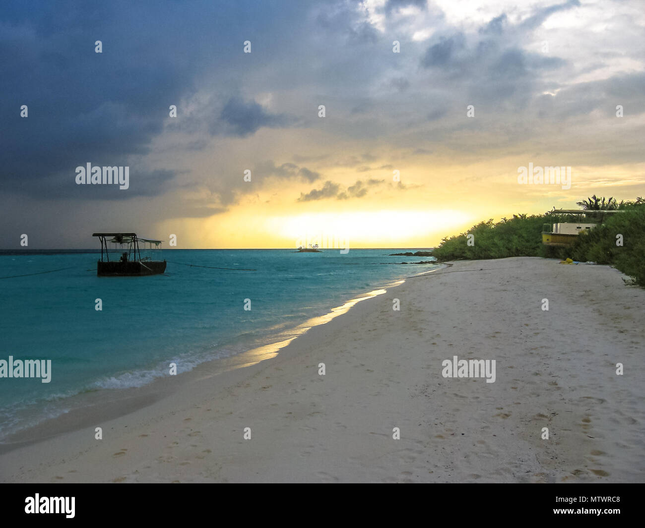 Maldives background. Sunset over the tropical sea and coral beach with ...