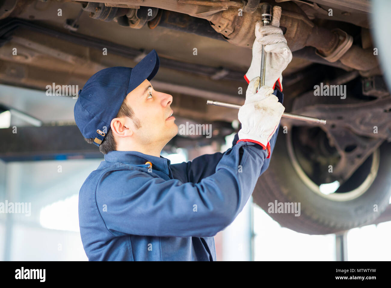 Mechanic repairing a lifted car Stock Photo - Alamy