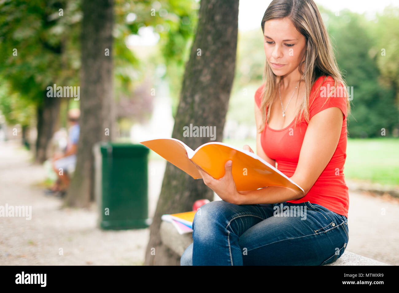 Outdoor portrait of a student reading a notebook Stock Photo - Alamy