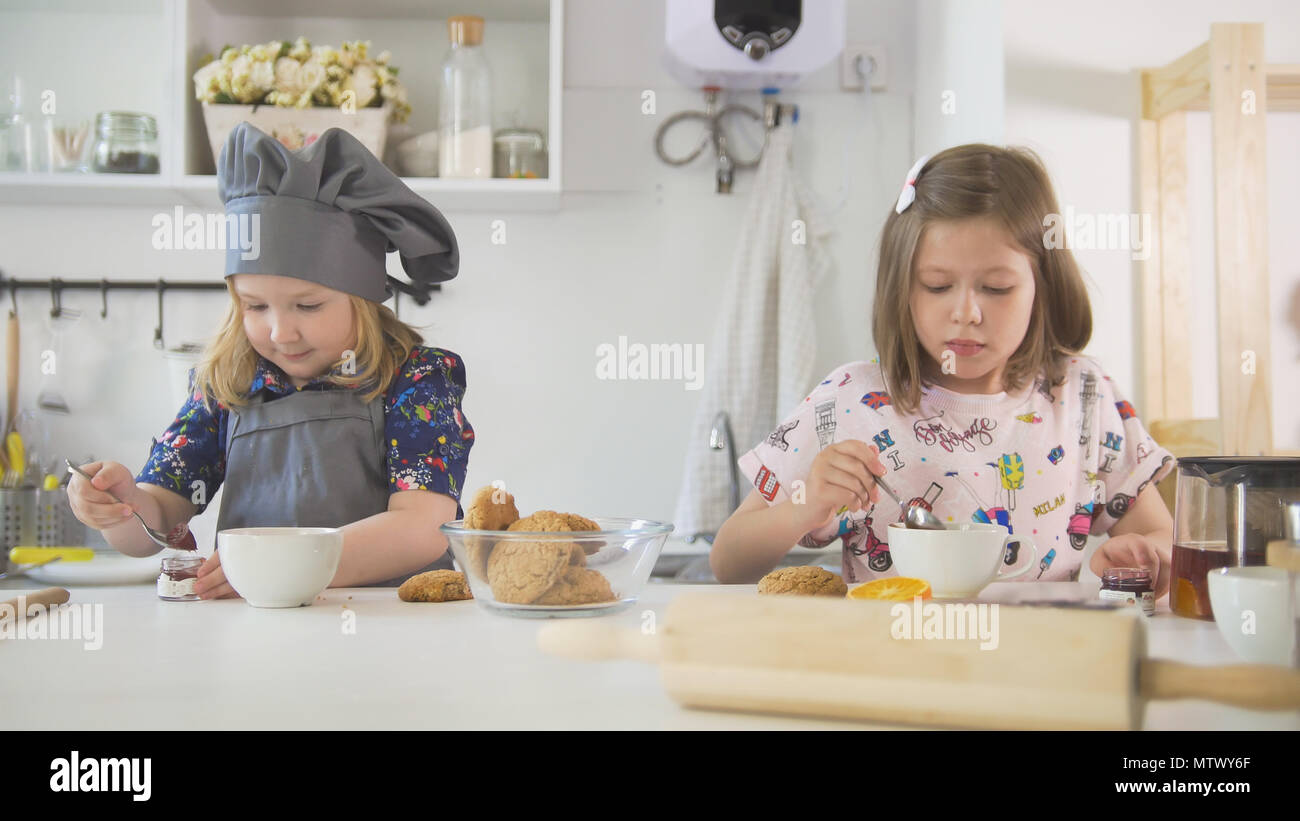 Two cute little girls decorating cookies with jam Stock Photo - Alamy