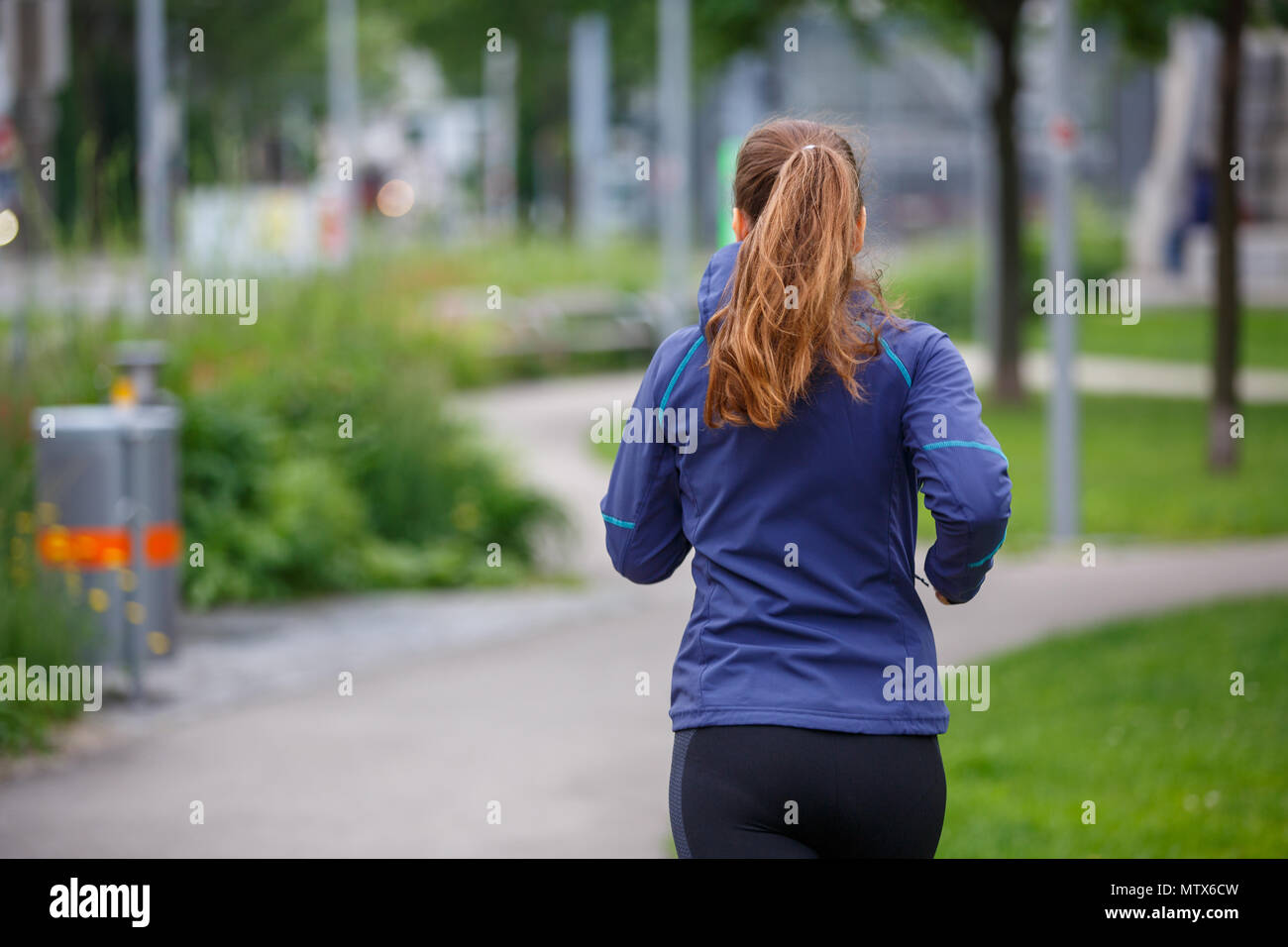 Young woman jogging in park in city. Rear view of running girl with ...