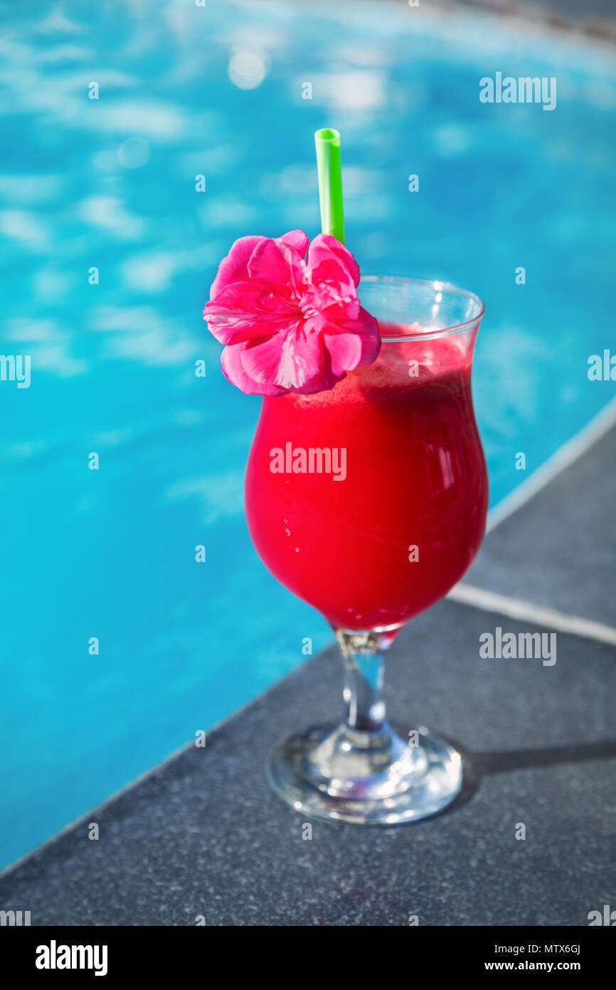 Glass of fresh watermelon smoothie juice drink on border of a swimming ...
