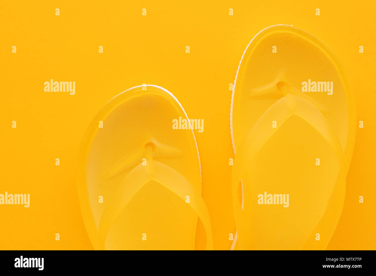 Top view of yellow flip flops pair on same color background with copy ...