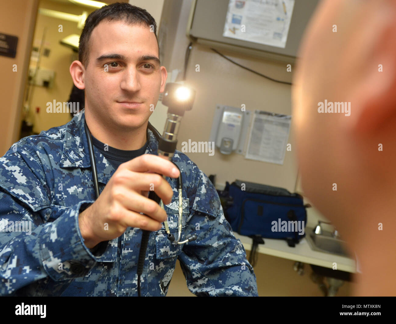 A U.S. Navy Hospital Corpsman conducts a physical health assessment on ...