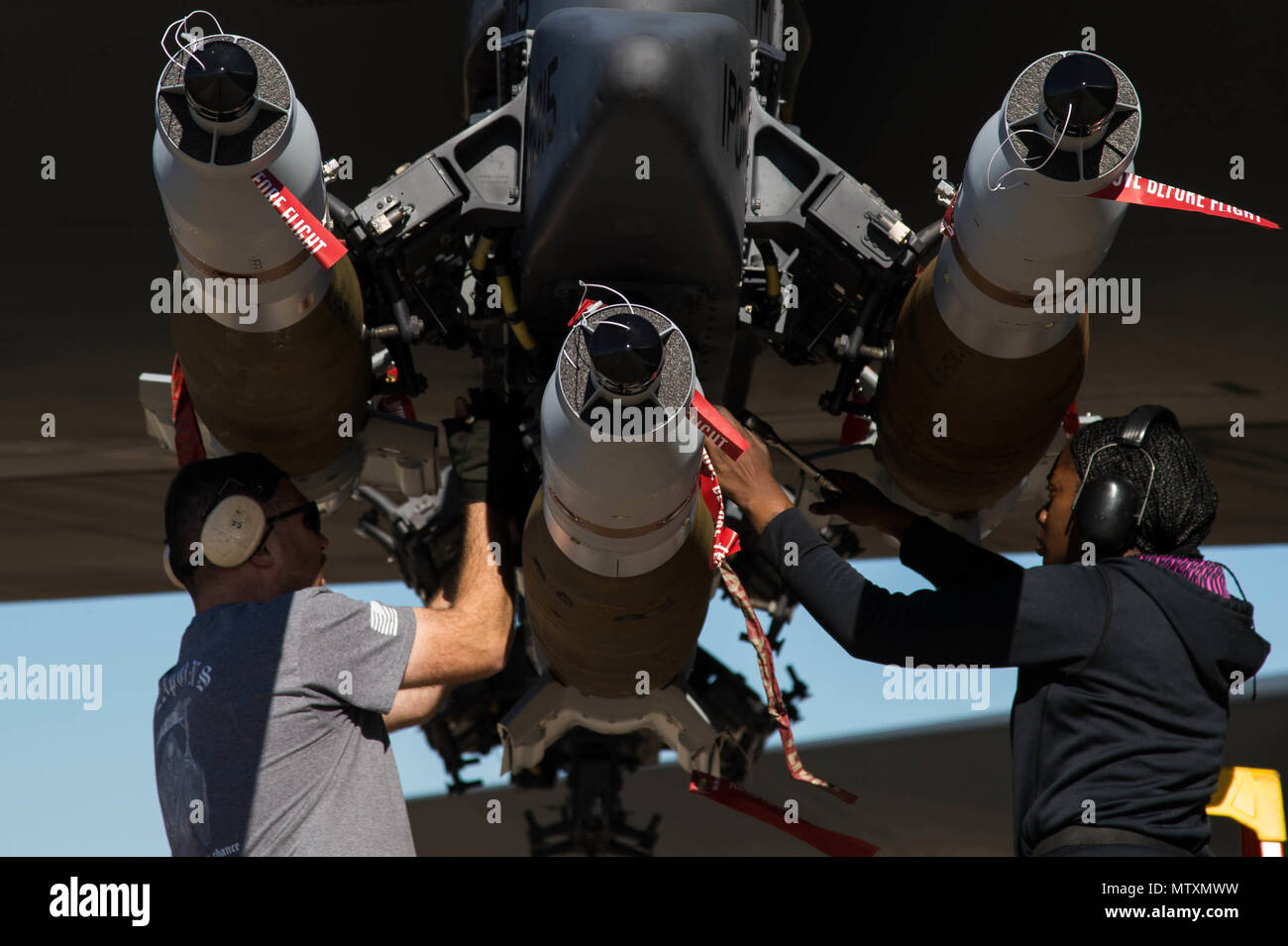 Airmen load three 500 pound bombs are loaded under the wing of a B-52 ...