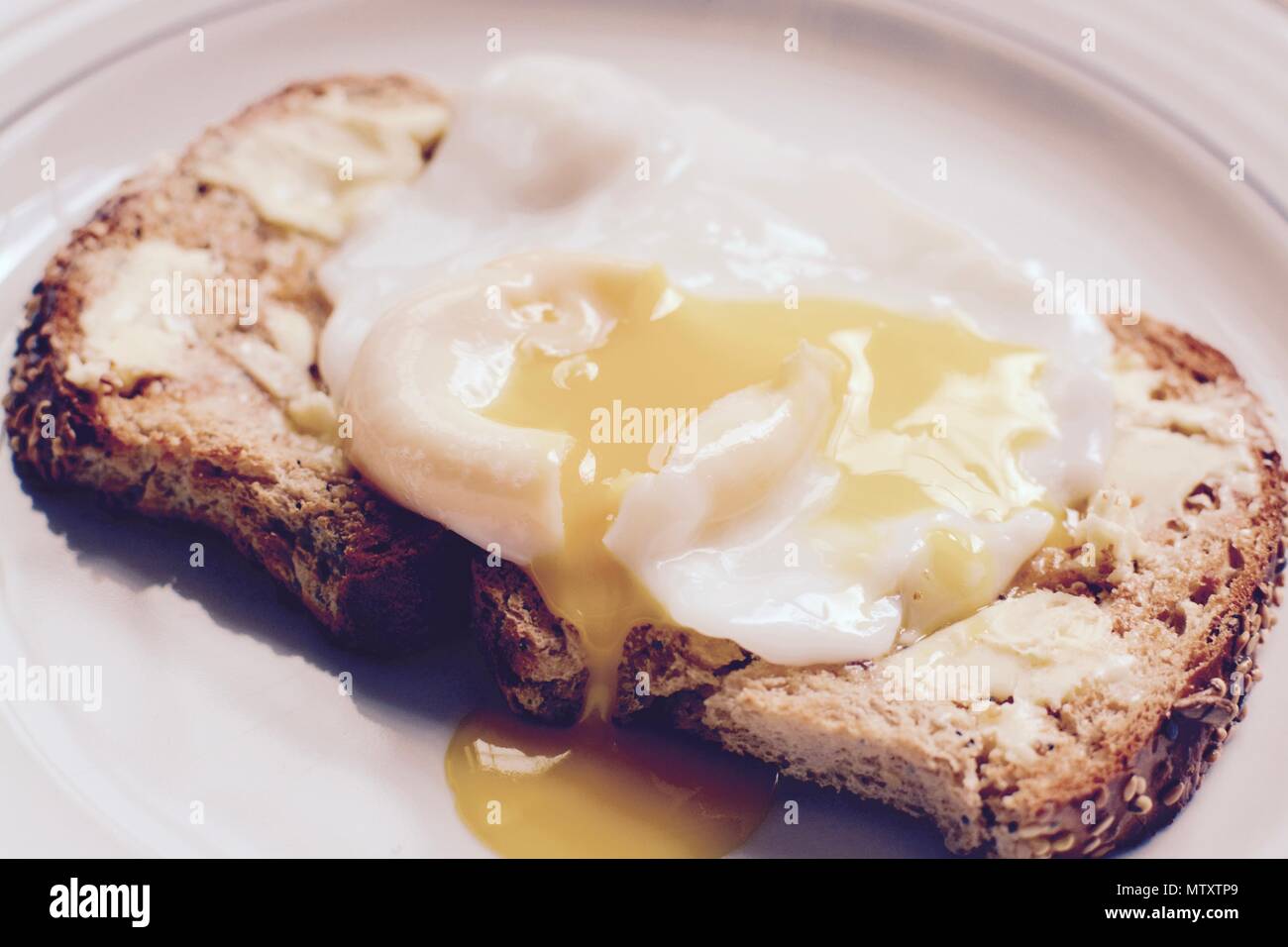 Runny poached egg on brown buttered toast - filter applied Stock Photo ...