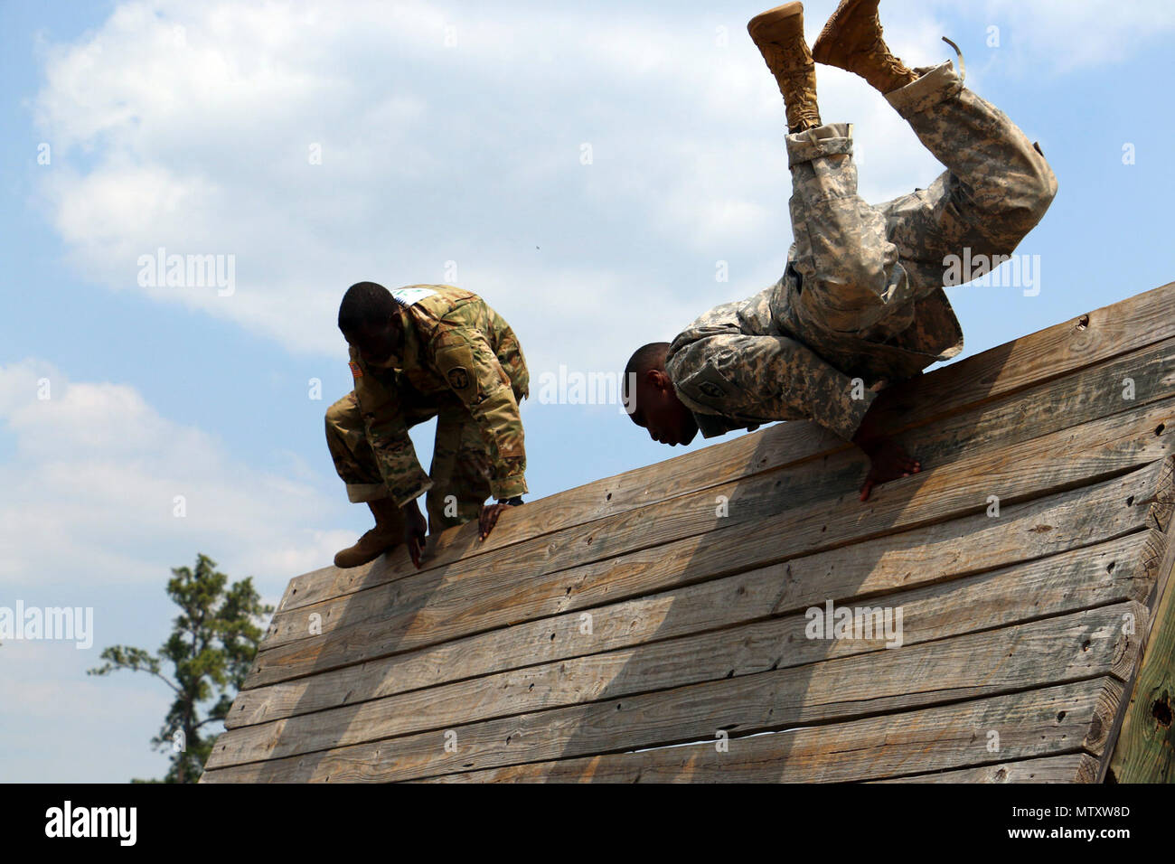Soldiers of 385th Military Police Battalion jump over a leaning wall ...