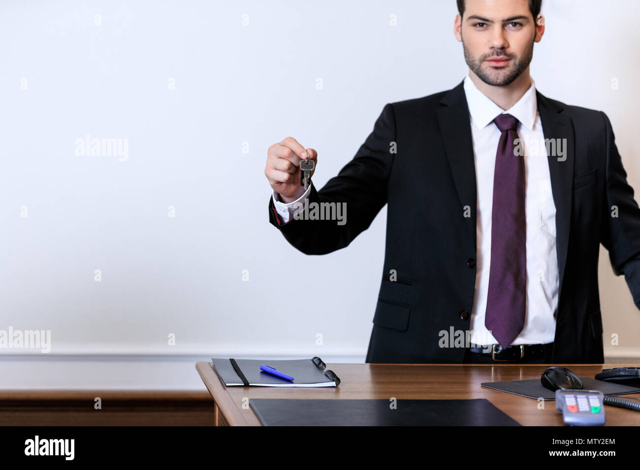 handsome receptionist holding key at reception desk Stock Photo - Alamy