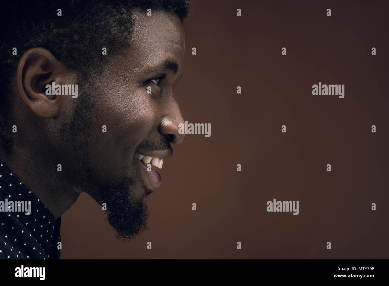 side view of smiling african american man isolated on brown Stock Photo ...