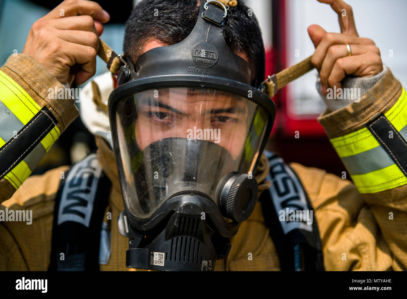 A firefighter from Central America puts on his protective gear prior to ...