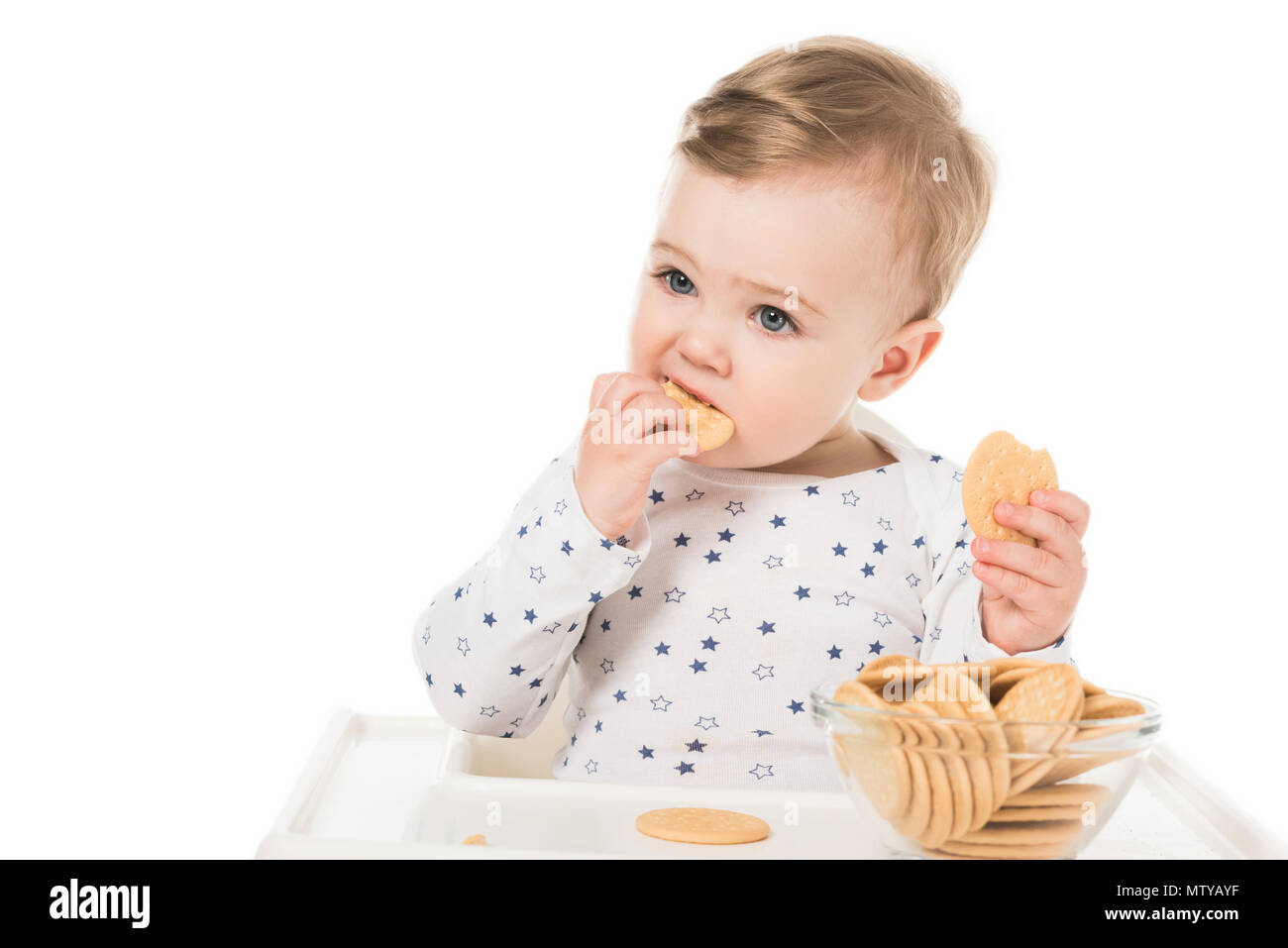 adorable baby boy eating cookies sitting in highchair isolated on white ...