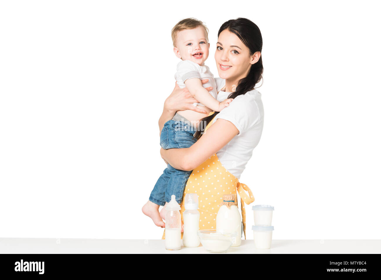 young mother in apron holding baby boy at table with children food ...