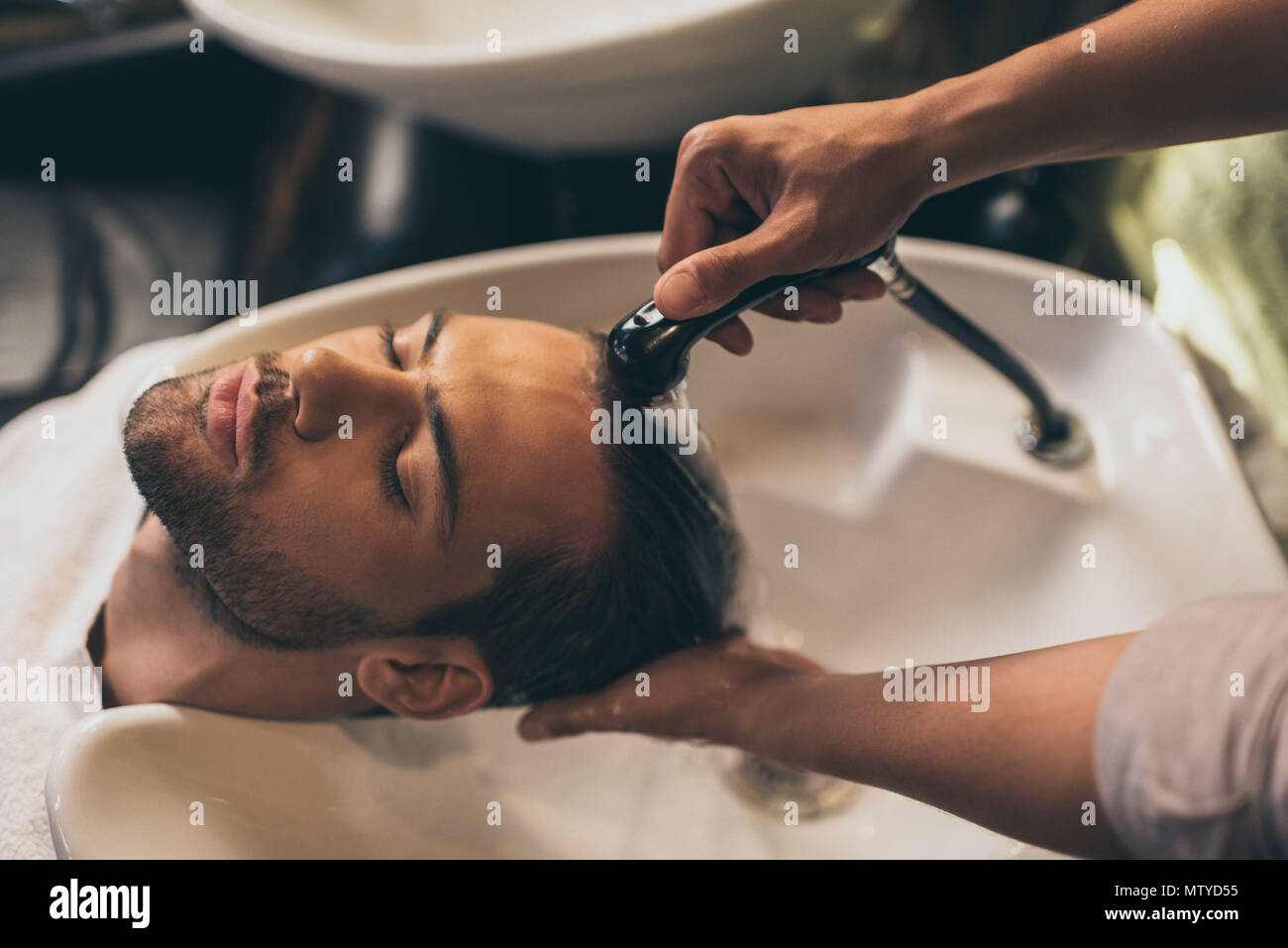 Cropped view hairstylist washing clients hair in barber shop Stock ...