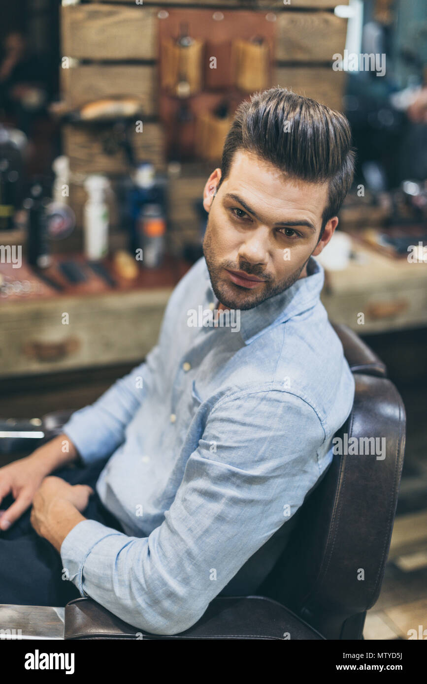 Portrait of handsome caucasian man with fashionable hairstyle at barber ...