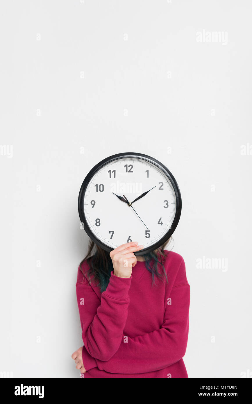 Woman holding clock over her face isolated on white Stock Photo - Alamy