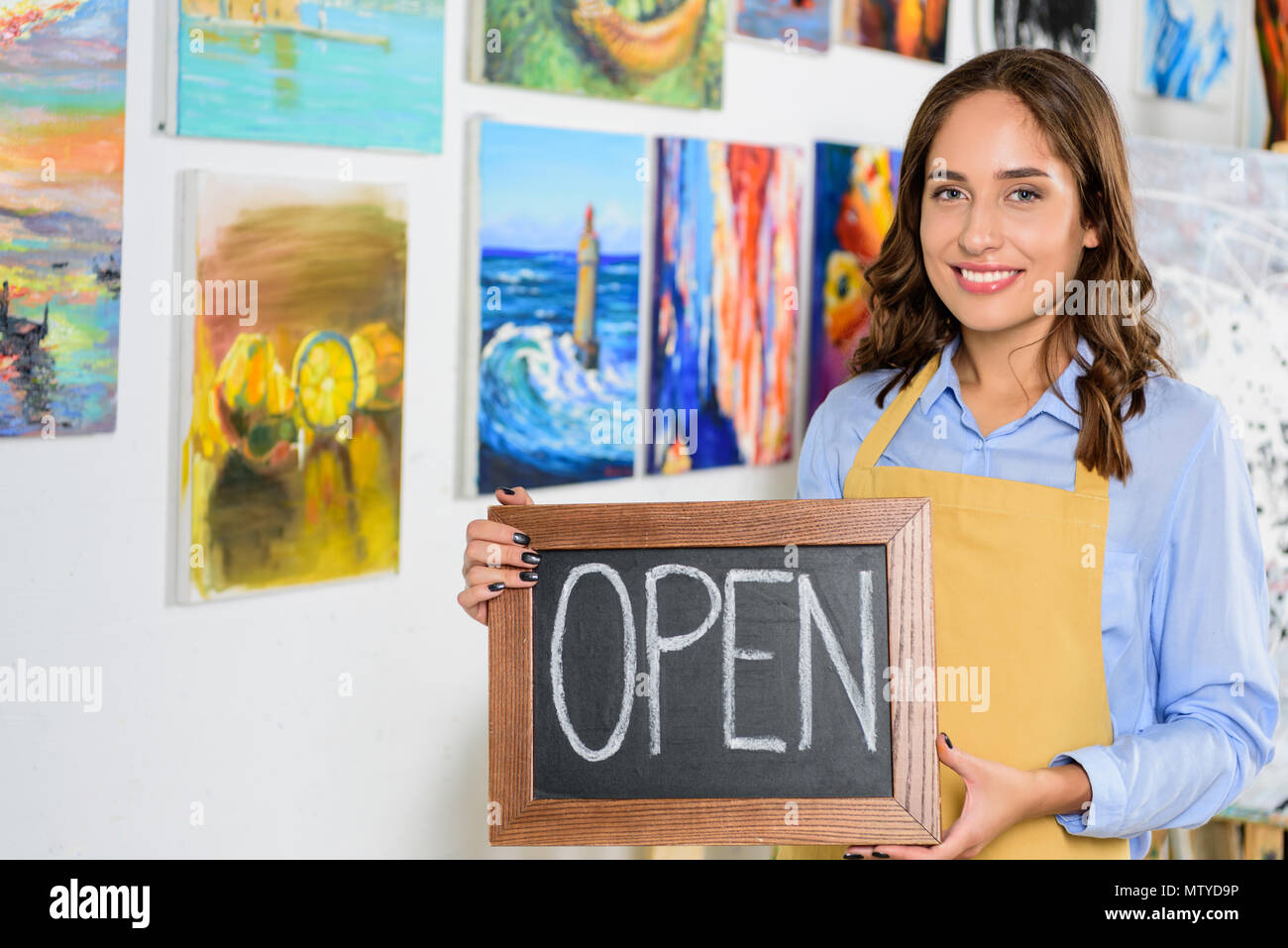 happy female artist holding signboard with word open in workshop Stock ...