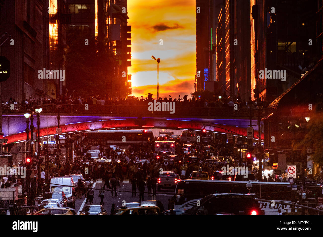A partially cloud obscured Manhattanhenge sun set. Manhattanhenge is ...