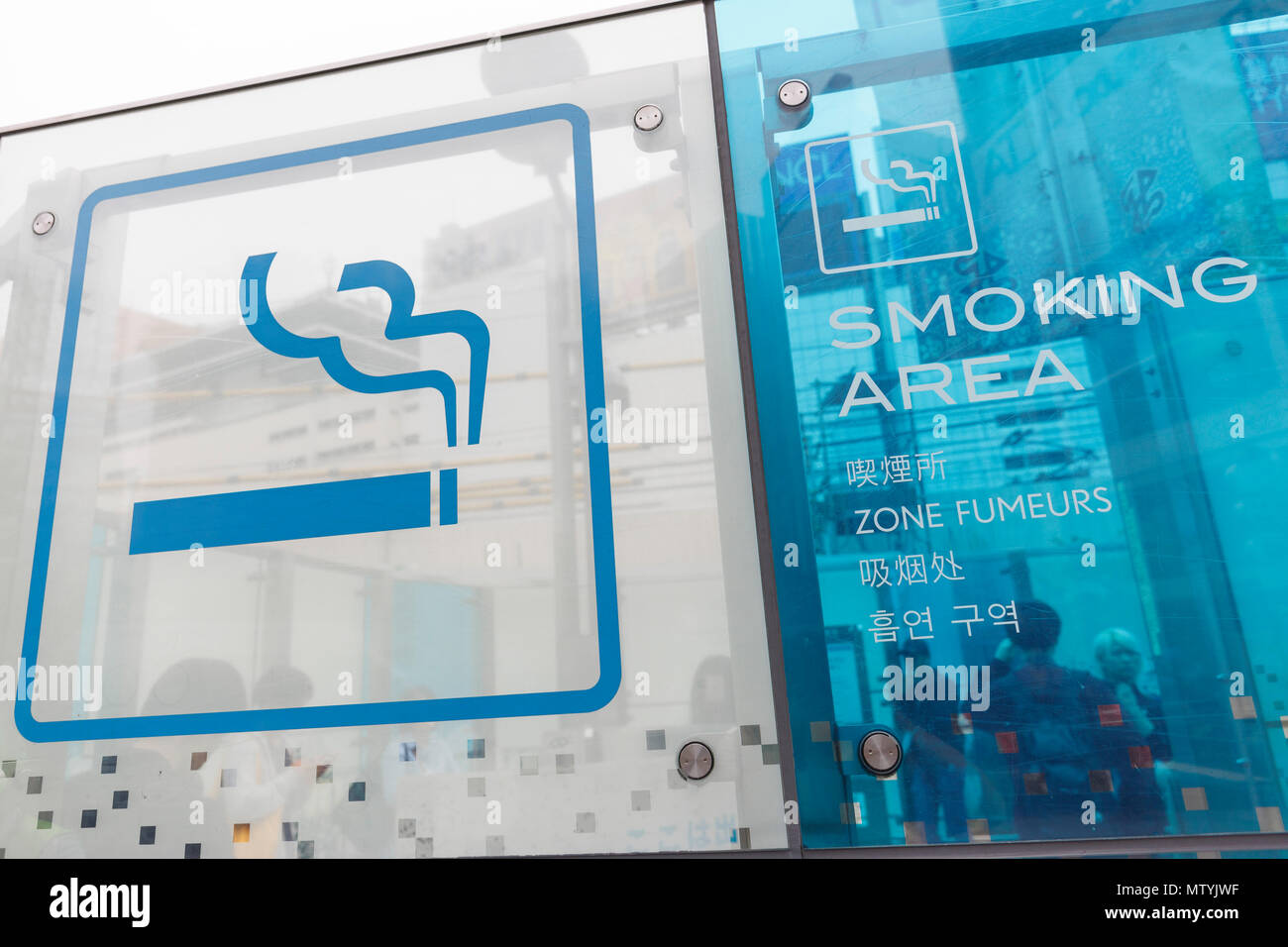 People smoke in a designated smoking area outside Shinjuku Station on ...