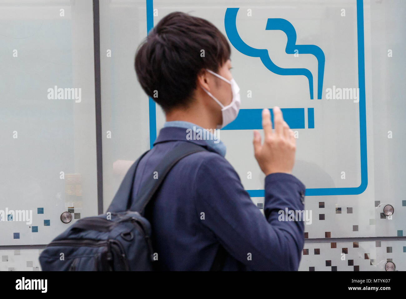 A man walks past a designated smoking area outside Shinjuku Station on ...
