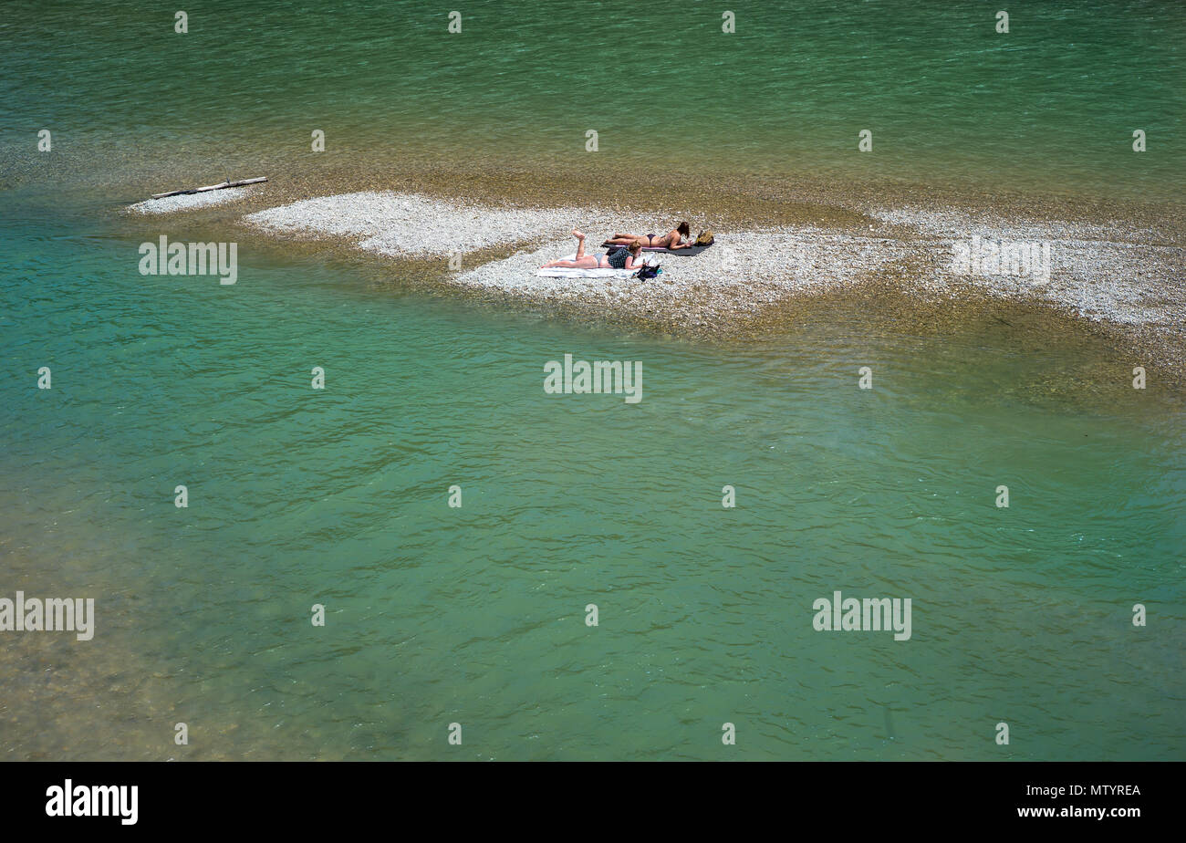 31 May 2018, Germany, Munich: Two sunbathers lying on a gravel bank ...