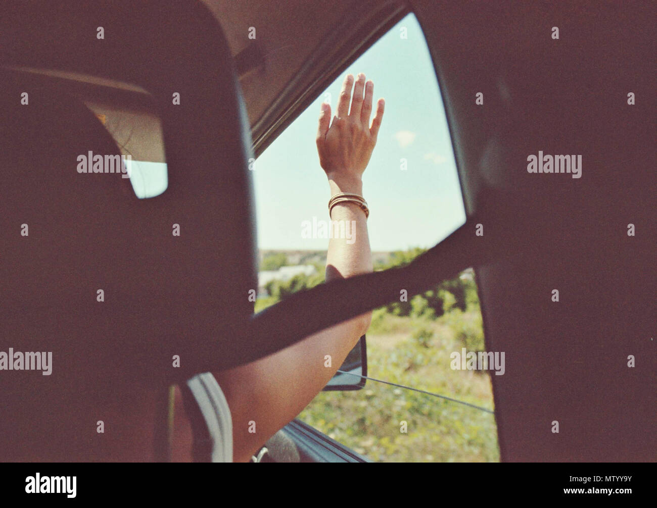 Woman waving out of a car window Stock Photo - Alamy