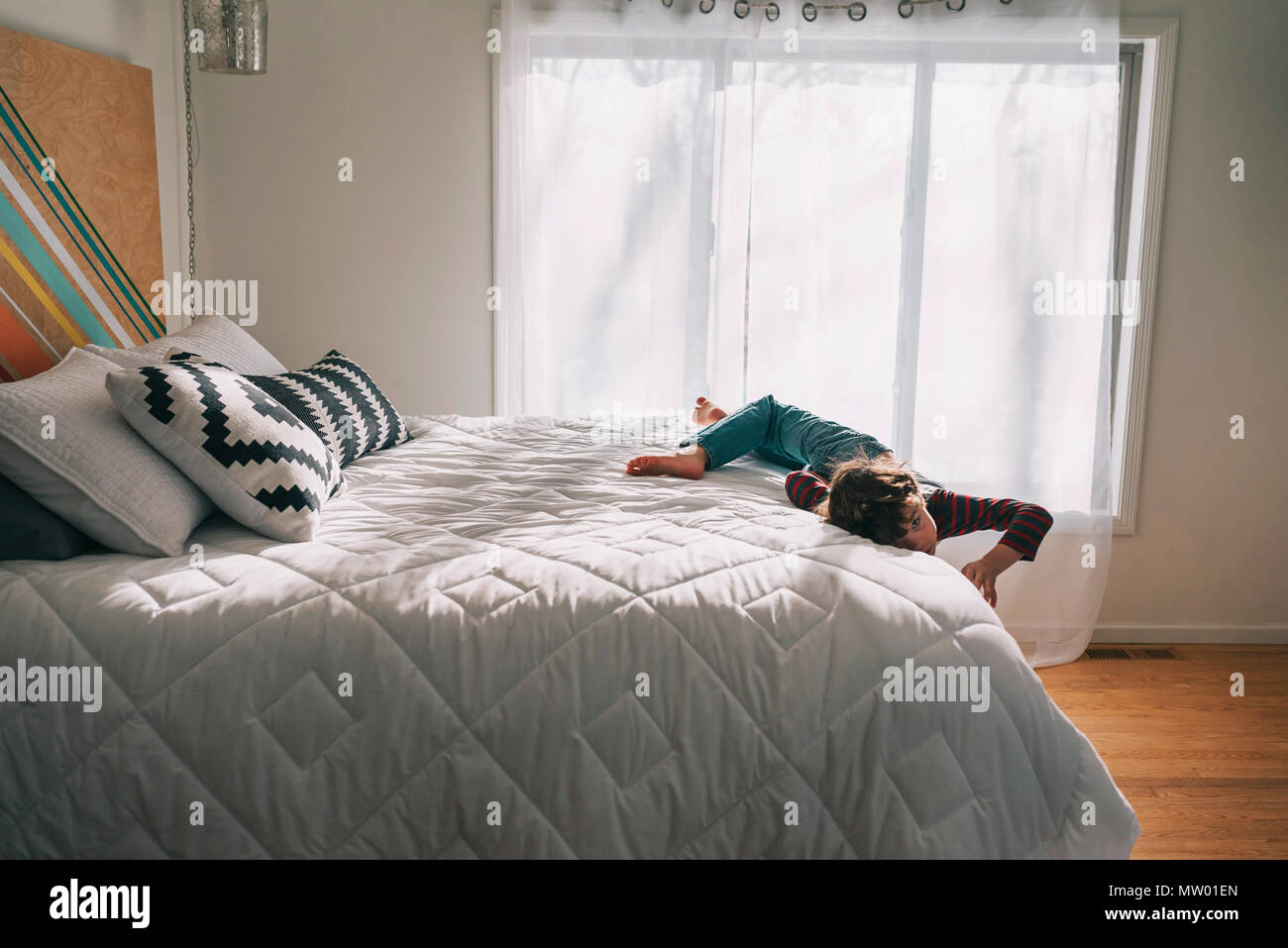 Boy rolling around on a bed Stock Photo - Alamy