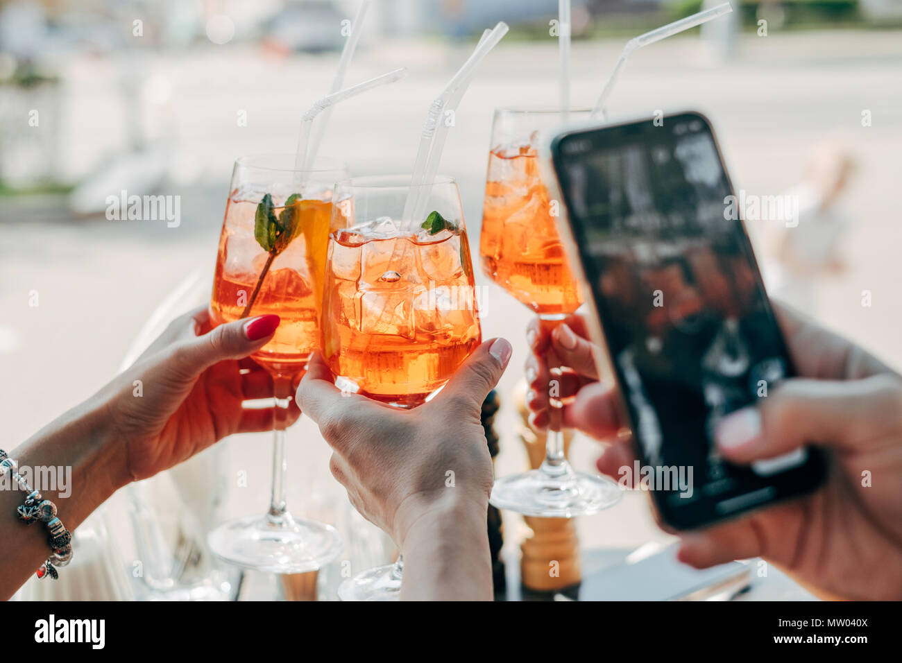 Three women making a celebratory toast with aperol spritz cocktails ...